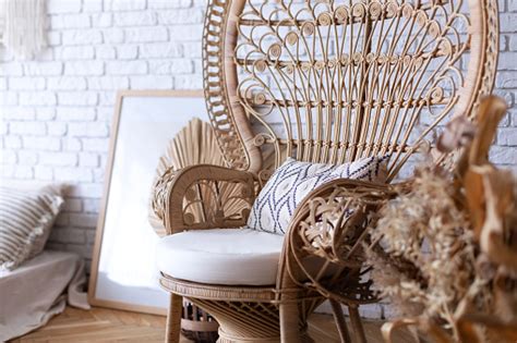 등나무 공작 의자가 있는 인테리어 디자인의 현대적인 보헤미안 룸 거실에 베개가 있는 나무 안락의자 에코 천연 가구 쿠션이 있는 고리 버들 세공 의자가 있는 아늑한 객실입니다