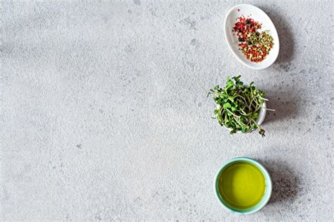 올리브 오일과 후추 믹스가 있는 그릇에 담긴 신선한 무 마이크로그린이 회색 배경에 있습니다 건강한 라이프 스타일 개념 비건 음식