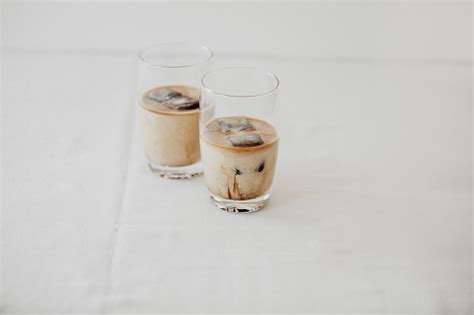 냉동된 커피 한 잔에 얼음 조각 상쾌한 여름 아이스 커피 음료를 만들기 위해 우유를 부 어 흰색 배경 고립 된 공간을 복사