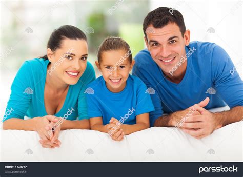 خانواده سه نفری شاد جوان که در خانه روی تخت خوابیده اند 1548777