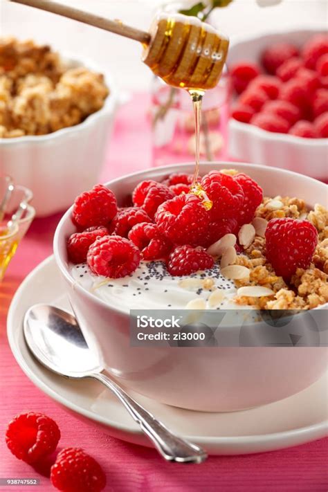 그 라 놀라 천연 요구르트 딸기 아몬드 플레이크와 양 귀 비 씨앗 분홍색 나무 테이블에 그릇에 벌 꿀과 부 맛있고 영양가 있는 아침 식사 또는 디저트입니다 0명에 대한 스톡