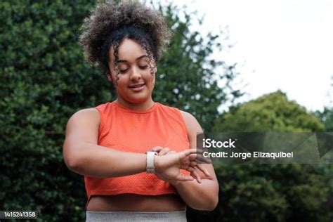 A Chubby Young Mixed Race Woman Is Standing In A London Park Checking