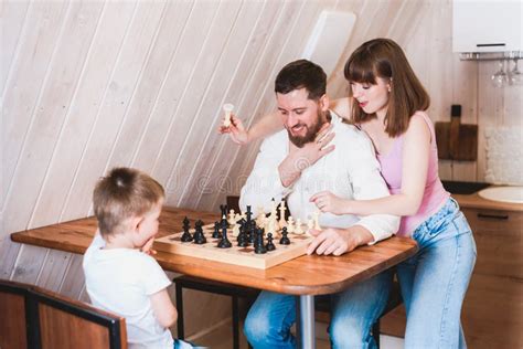 Pregnant Mom Watching Dad And Son Play Chess At The Table Stock Image