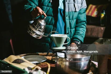 남자는 코트를 입고 하 고 다른 방법으로 커피를 붓는 것은 물방울 이라고 합니다 커피 분쇄기 커피 스탠드 및 나무 테이블에 붓는