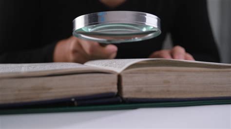 Close Up Of A Woman Looking Through A Magnifying Glass At A Textbook