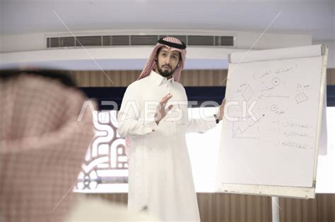 مدرب عربي سعودي يقوم بالشرح لمتدربين سعوديين خليجيين على سبورة بيضاء