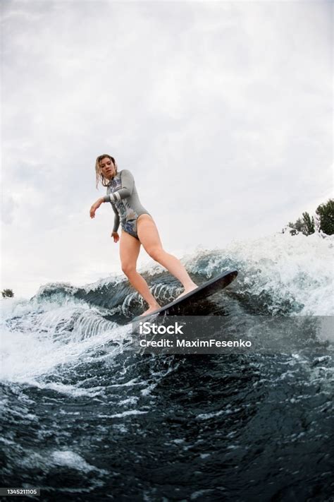 회색 수영복을 입은 유연한 여성은 웨이크 서핑 보드의 파도에 힘차게 균형을 유지합니다 곡예 활동에 대한 스톡 사진 및 기타 이미지 곡예 활동 서핑 수상 스포츠 강