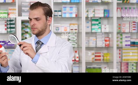 Druggist Man Checking Expiration Date Of Drug Using Magnifying Glass In