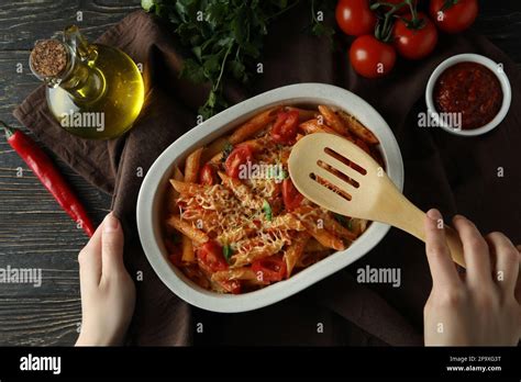 Female Hands Hold Kitchen Spatula Over The Tray With Pasta With Tomato