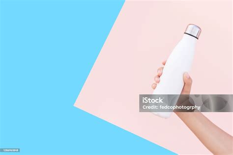 파스텔 핑크와 블루 컬러의 배경에 흰색의 재사용 강철 열병병을 들고 여성의 손의 클로즈업 복사 공간 강철에 대한 스톡 사진 및