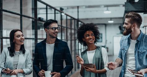 스마트 캐주얼 복장을 입은 젊은 동료들이 사무실 복도에 서서 무언가를 논의하고 있다 사진 Unsplash의 사업 이미지