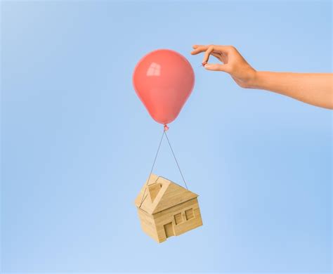Premium Photo Hand Exploding A Balloon Tied To A Wooden House On A