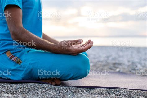 건강한 젊은이는 바다 앞에서 요가 연꽃 포즈를 취하고 앉아 일출 해변에서 명상하고 있습니다 건강한 생활방식에 대한 스톡 사진 및