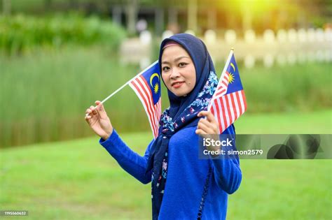 マレーシア国旗を持つカメラを見てヒジャーブを持つ美しい若いイスラム教徒の女性 1人のストックフォトや画像を多数ご用意 1人 お祝い