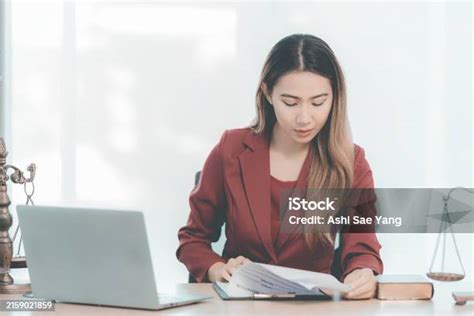 여성 변호사 또는 판사가 문서나 계약서를 확인하고 수첩에 메모를 하고 법률 사무소에서 망치와 저울을 들고 노트북을 옆에 두고 일하고 있습니다 Conference On The