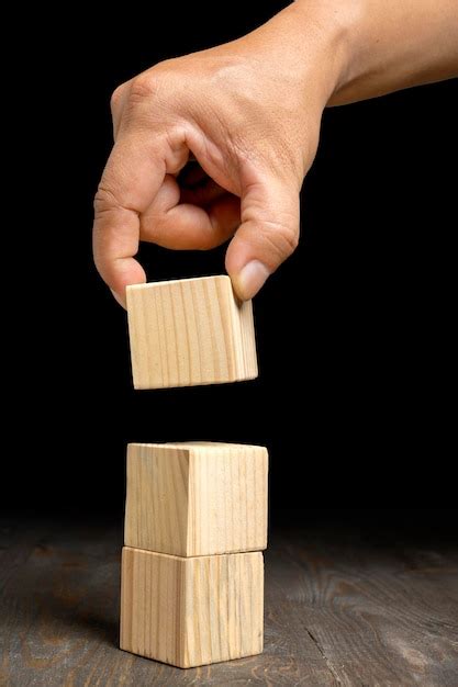 Premium Photo A Human Hand Put A Stack Of Wooden Cubes
