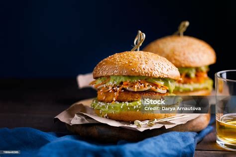 진한 파란색 배경에 아보카도 과카몰리 소스와 당근 슬로를 곁들인 비건 고구마 병아리콩 버거 야채 햄버거에 대한 스톡 사진 및