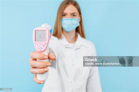 보호 마스크의 여성 의사가 비접촉 적외선 온도계를 사용하여 온도를 측정합니다 간호사에 대한 스톡 사진 및 기타 이미지 간호사