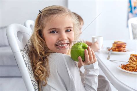 有绿苹果的可爱小孩在和家人一起吃早饭时看高清图片下载 正版图片503315796 摄图网