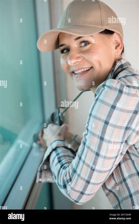 Happy Woman Using Silicone To Fix A Window Stock Photo Alamy