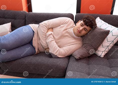 Non Binary Man Suffering For Stomach Ache Lying On Sofa At Home Stock