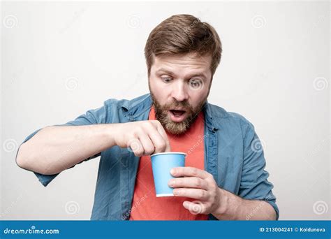 Shocked Man With A Paper Cup In Hand Takes Something Out Of Freshly