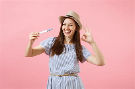 파란 드레스에 흥분된 행복 한 여자 모자 잡고 손 임신 테스트 분홍색 바탕에 고립 된 보고 의료 의료 부인과 임신 임신 출산 사람들 개념 공간에 복사 합니다 건강 진단에