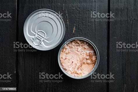 통조림 야생 옐로 핀 참치 주석 캔에 검은 나무 테이블 배경에 상단 보기 평면 누워 카피 스페이스와 텍스트 공간을 가진 0명에