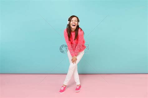穿着针织玫瑰毛衣白色裤子耳机的快乐年轻女子的全长肖像高清图片下载 正版图片505696219 摄图网