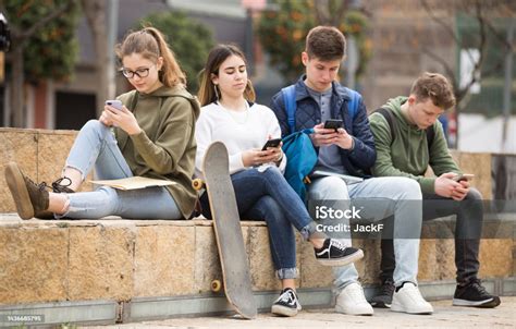 네 명의 청소년이 거리에서 스마트폰 화면을 열정적으로 바라봅니다 12 13세에 대한 스톡 사진 및 기타 이미지 12 13세 14 15 살 16 17 살 Istock