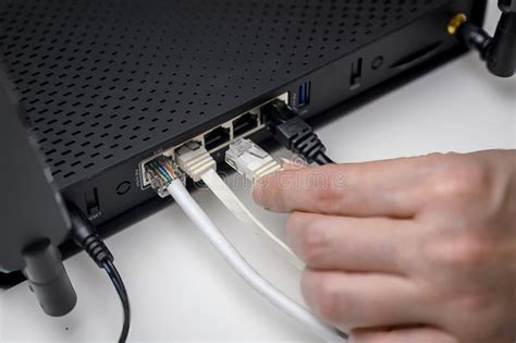 A Close Up Of A Person Plugging Wires Into A Router A Person Connects To A Wireless Router
