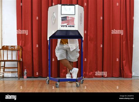 A Man Stands Behind A Voting Privacy Booth To Fill Out A Ballot In