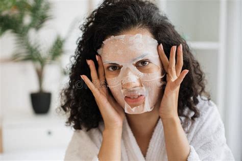Woman In After Shower Outfit Touching Cosmetic Mask Fixed On Face Stock
