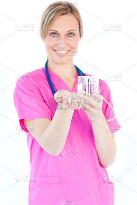 明亮的女护士拿着药丸和一杯水对着镜头微笑