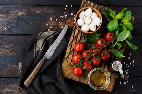 오래된 나무 배경에 신선한 체리 토마토 바질 잎 모짜렐라 치즈와 올리브 오일 카프리즈 샐러드 재료 선택적 초점 그린 올리브에