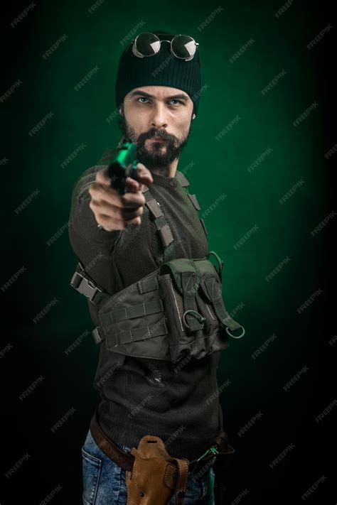 Premium Photo Portrait Of Young Man Aiming Pistol Standing Against