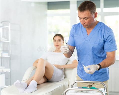 Surgeon Makes An Injection With Syringe Into Knee Of Female Patient In