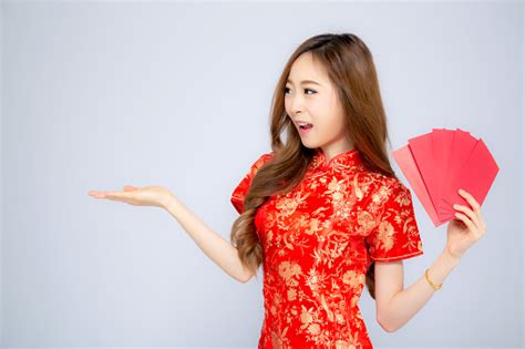 아름 다운 초상화 아시아 여자 치파오 드레스 빨간 봉투를 들고 뭔가 제시 하 고 공간 흰색 배경 행복 한 중국 새 해 휴일