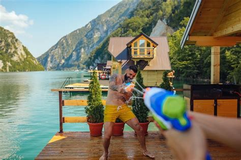 Premium Photo Two People Having Fun Splashing With Squirt Guns Outdoors