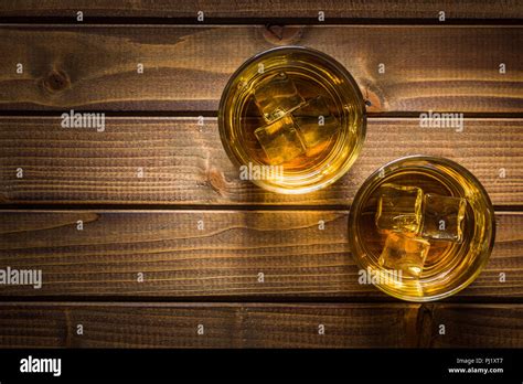 Glass Of Alcoholic Drink With Ice Cubes On Wooden Table Whiskey In
