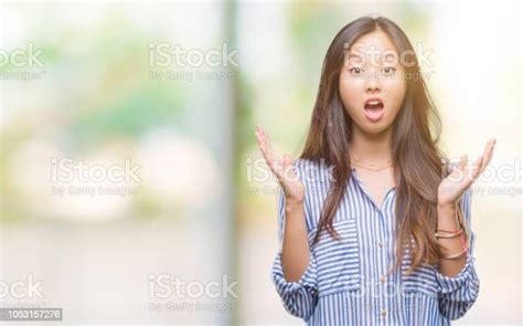 미친을 축 하 하 고 무기와 성공을 위한 흥분 비명 제기 및 오픈 눈 깜짝 놀라게 격리 된 배경 위에 젊은 아시아 여자 우승자