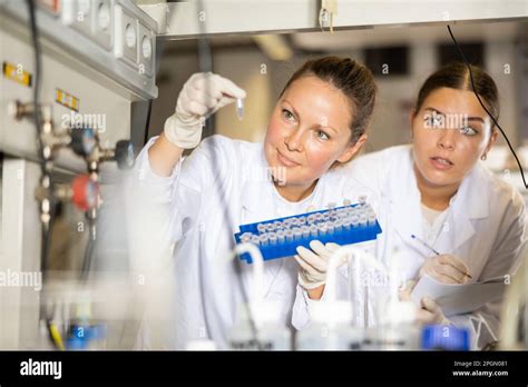 Two Female Scientists Conduct A Chemical Experiment Together And Write Down Test Results Stock
