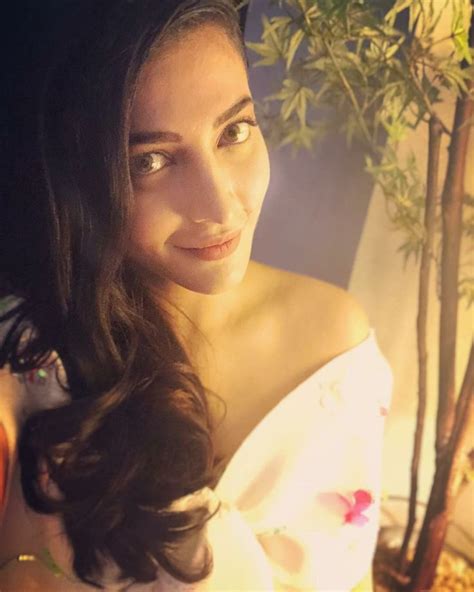 A Woman With Long Dark Hair Wearing A White Top And Looking At The