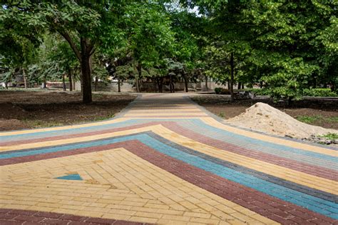 공원에서 색깔의 콘크리트 포장 슬래브를 누워 전문 노동자 벽돌 층은 수평 모래 기초 기지에 보도를위한 새로운 타일과 포장 슬래브를 설치하고있습니다 0명에 대한 스톡 사진 및