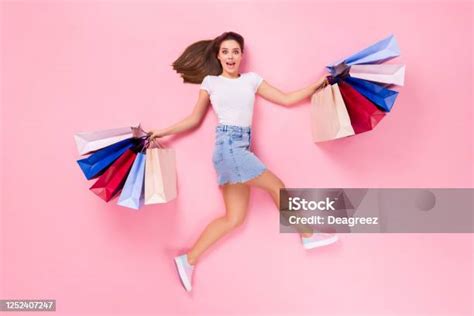 상단 높은 각도 보기 전신 사진 의 놀라운 펑키 소녀 감동 블랙 프라이데이 특가 쇼핑 가방 누워 산책 이동 빠른 착용 화이트 티셔츠 데님 고립 된 파스텔 컬러 배경 블랙