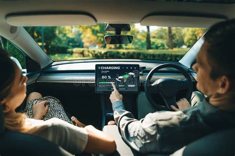 Electric Car Driver Checks Battery Charging Status App Screen In Car