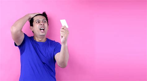 신용 카드 공간을 들고 젊은 잘생긴 아시아 남자는 깜짝 얼굴로 충격에 무서워 두려워하고 스튜디오에서 분홍색 배경에 두려움 표정으로 흥분 복사 공간 가계에 대한 스톡 사진 및
