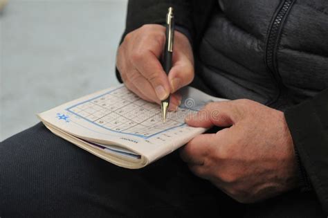 senior solving number puzzel during metro train jjourney editorial