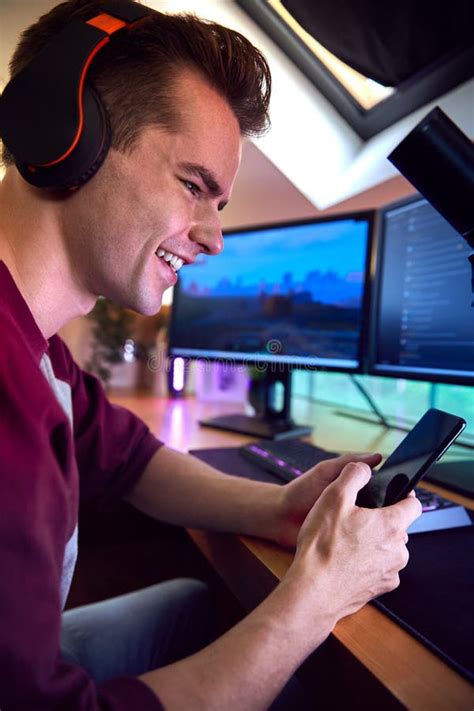 Man With Mobile Phone Gaming At Home Sitting At Desk With Multiple Monitors Stock Image Image Man With Mobile Phone Gaming At Home Sitting At Desk With Multiple Monitors Stock Image Image