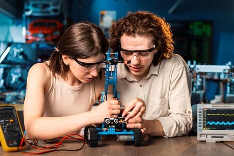 Free Photo Young Man And Woman In Protective Glasses Doing Experiments In Robotics In A